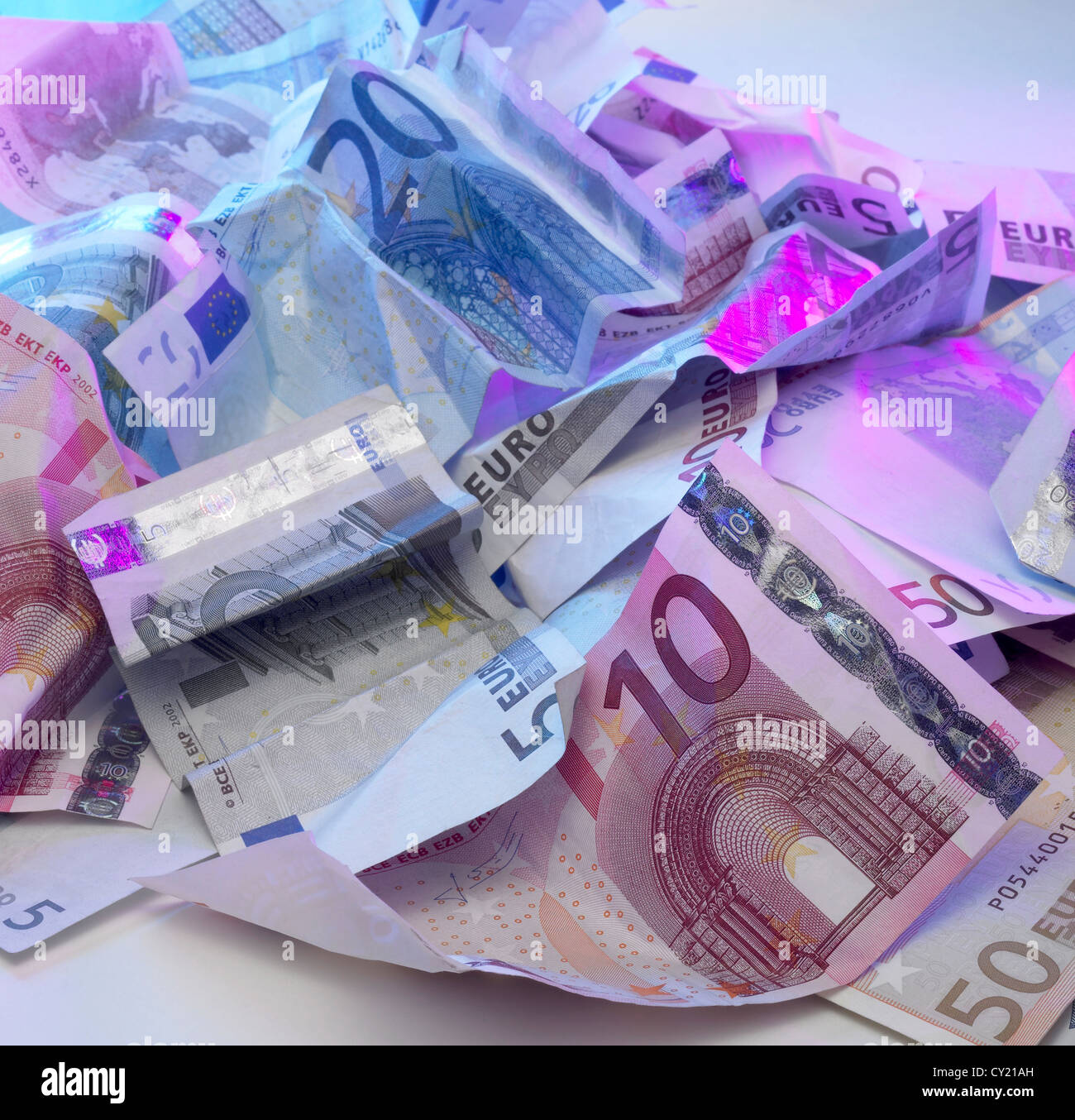 studio photography of crumbled euro banknotes illuminated with colored ...