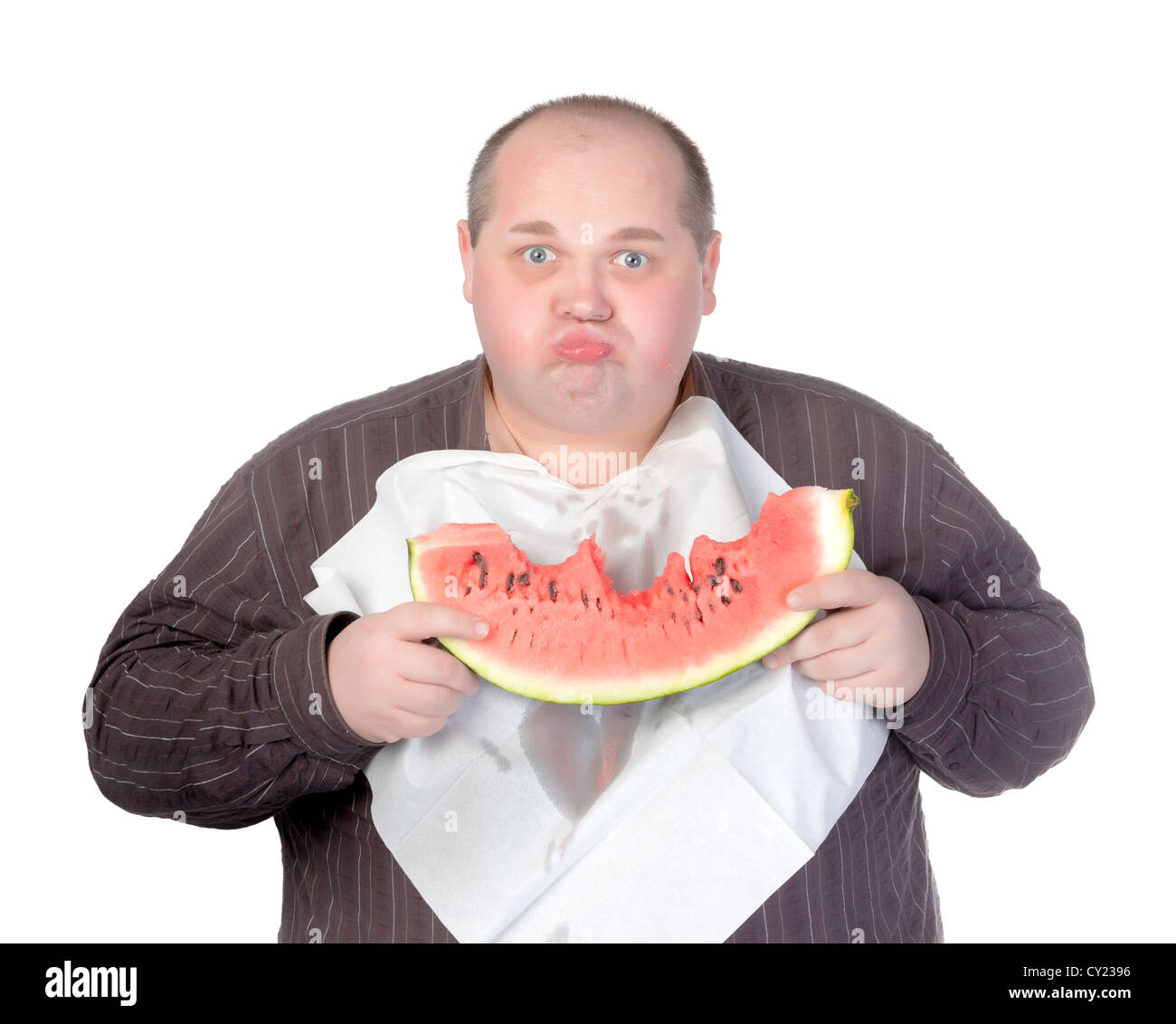 Obese man with a serviette bib around his neck standing eating a large ...