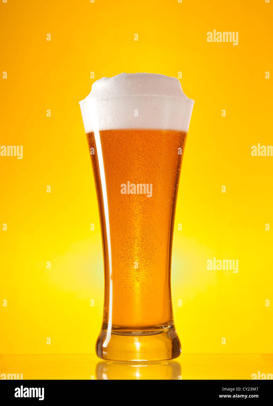 Full glass of beer with froth over yellow background Stock Photo - Alamy