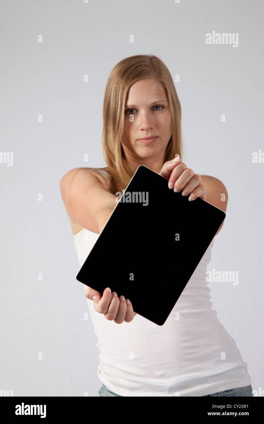 Blond woman in a white blouse, standing and holding a computer tablet ...