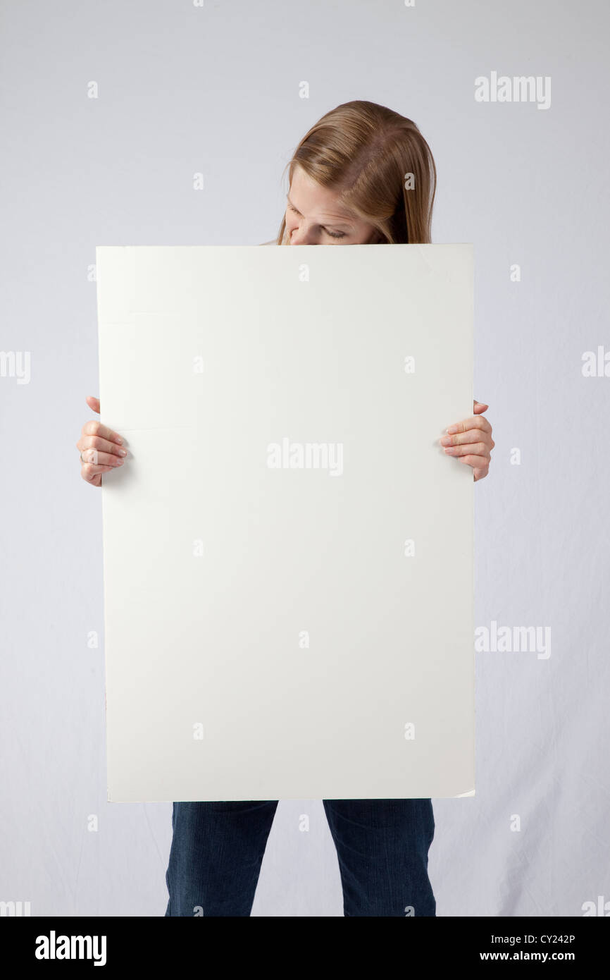 Pretty blond woman sitting and holding a white sign that is blank ...