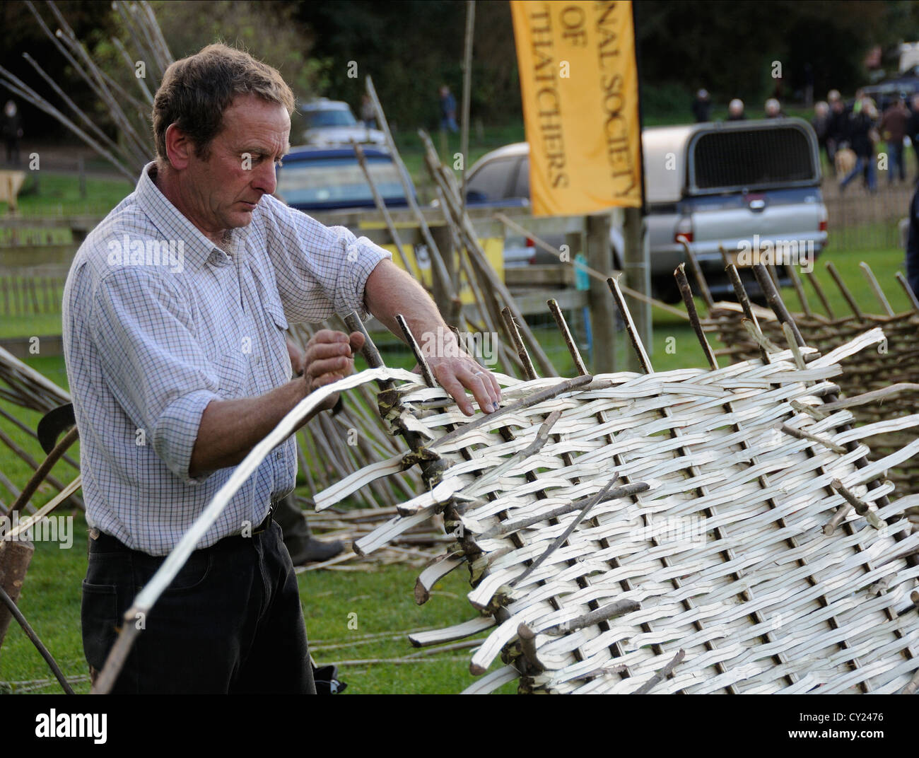 Hurdle maker threading split ash into a hurdle for sheep pens and ...