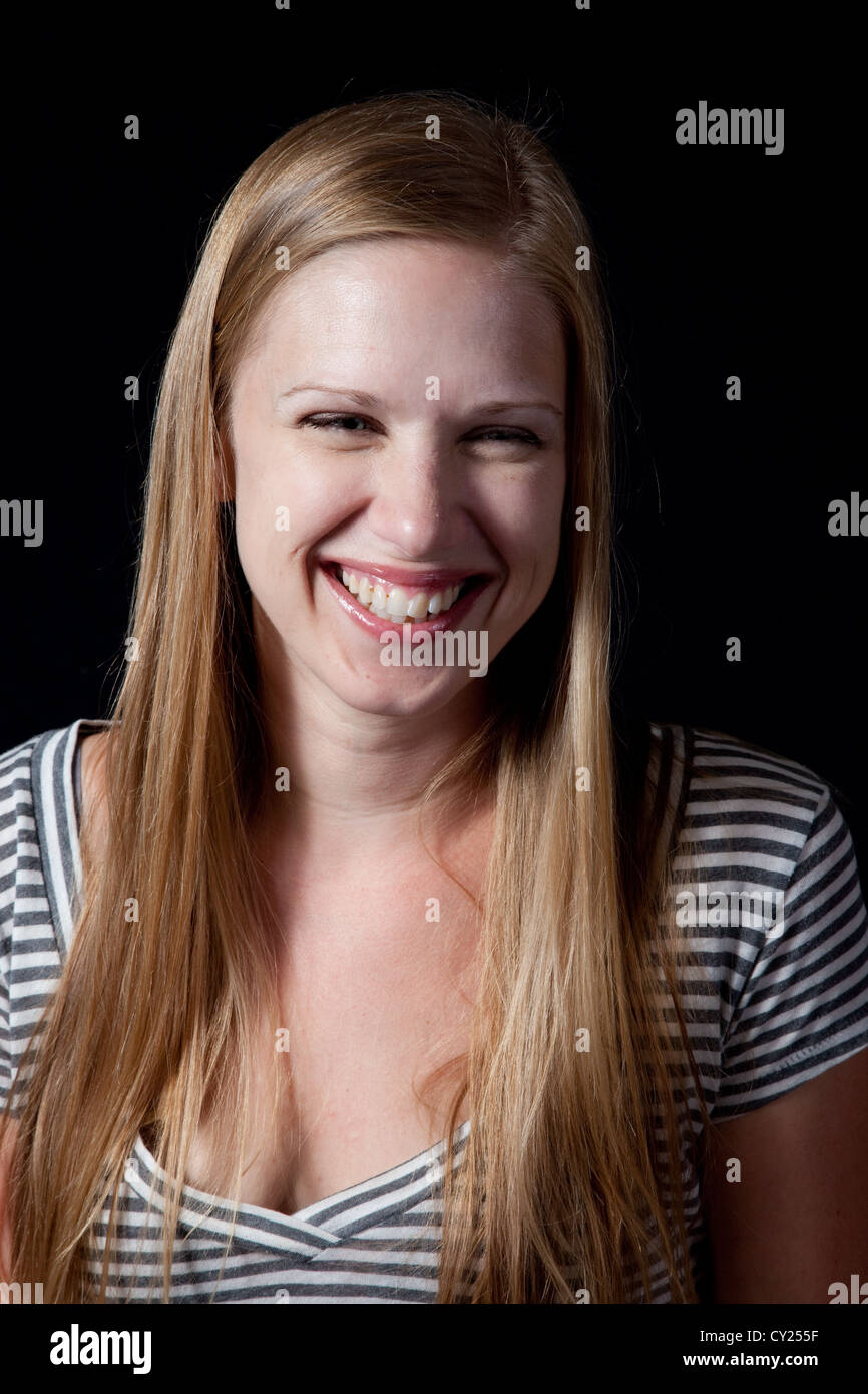 Pretty blond woman against a black background, with a happy fun laugh ...