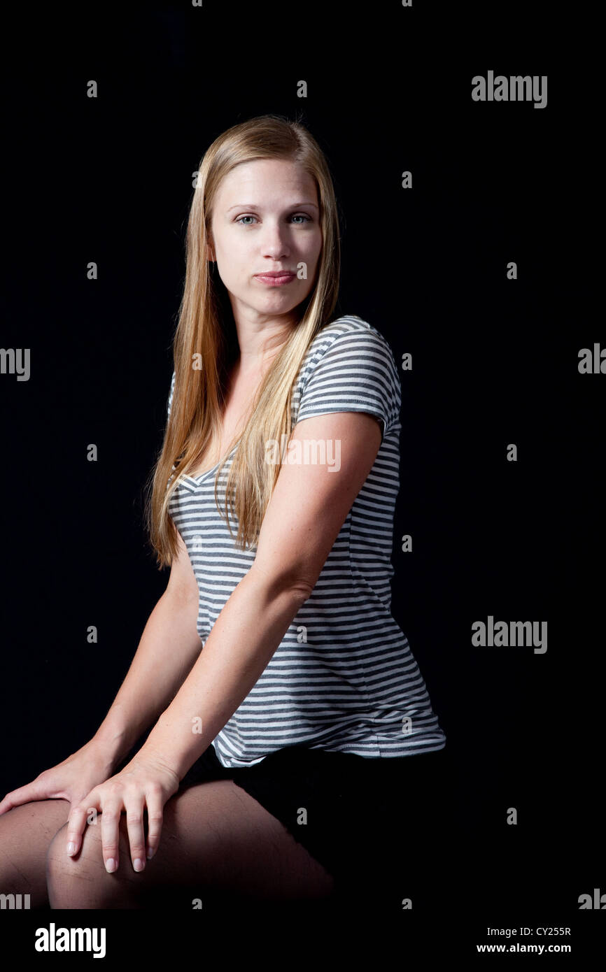 Pretty blond woman against a black background, with a sober and ...
