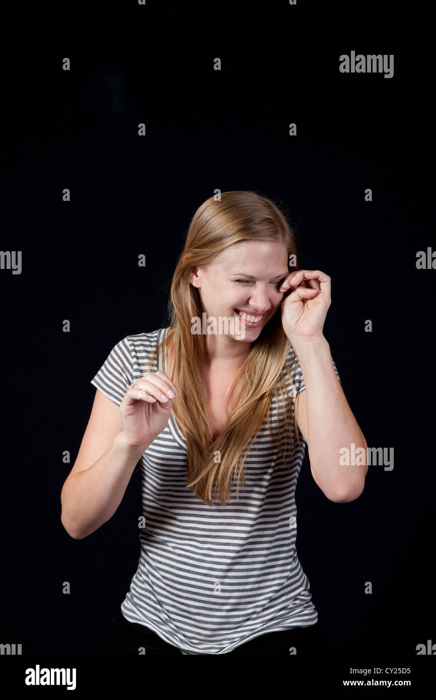 Pretty blond woman against a black background, with a happy smile and a playful giggle Stock ...