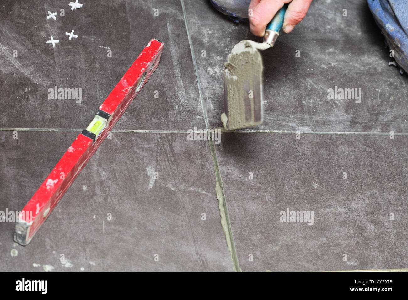 level Construction worker is tiling at home, tile floor adhesive Stock ...