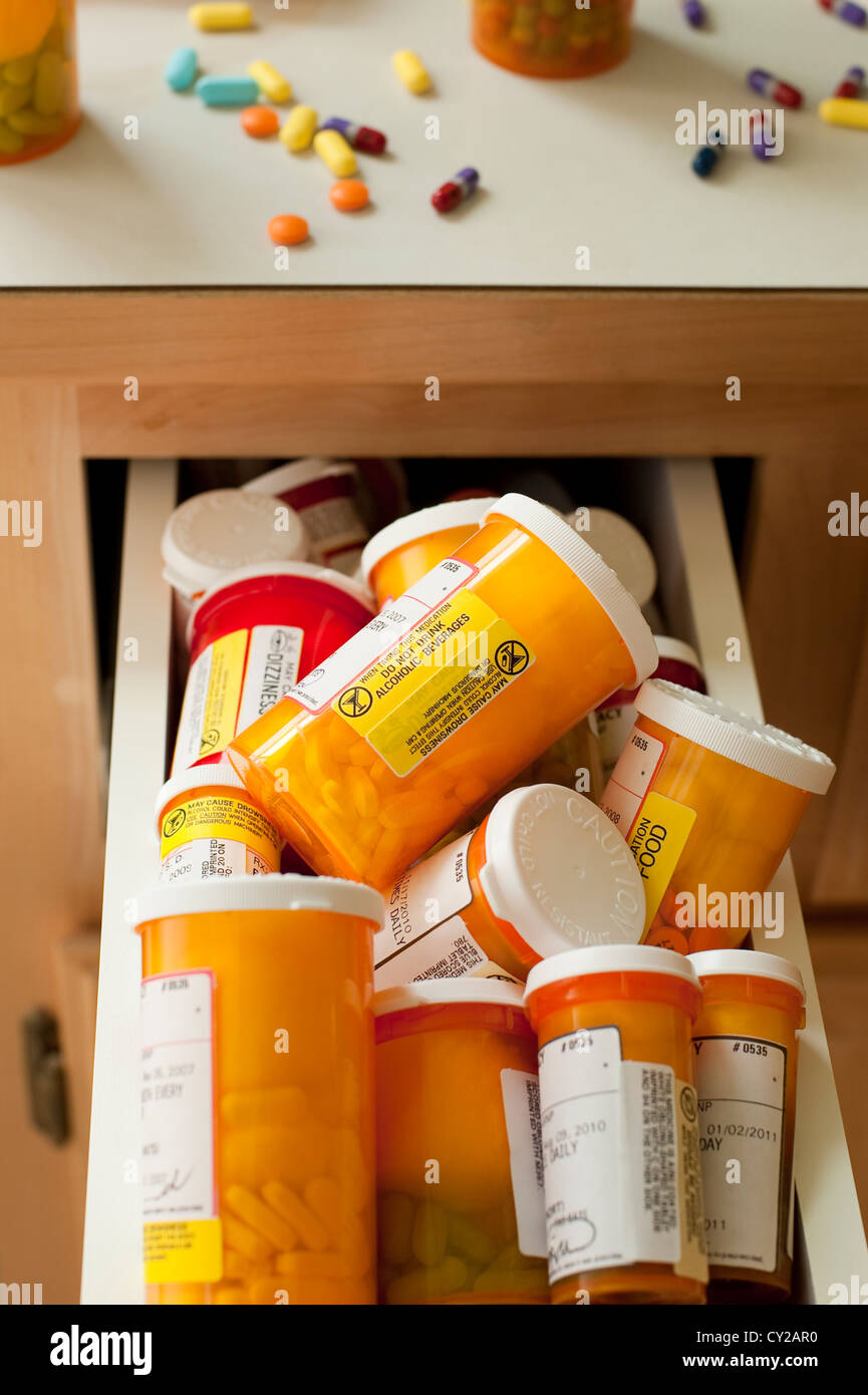 Pills and pill bottles scattered over sink counter in bathroom with ...