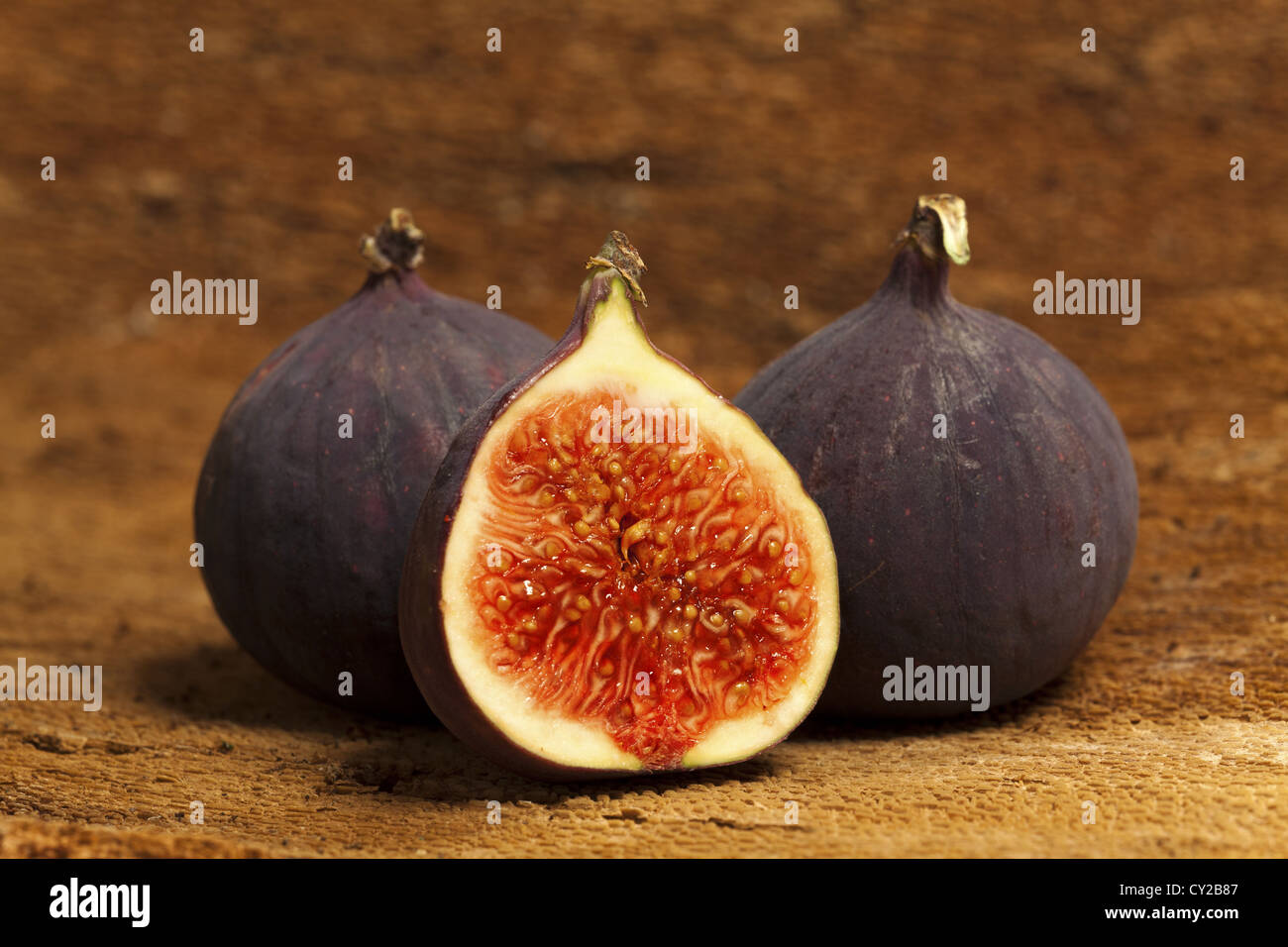 Two whole and a halved fig on old tree bark as background Stock Photo ...