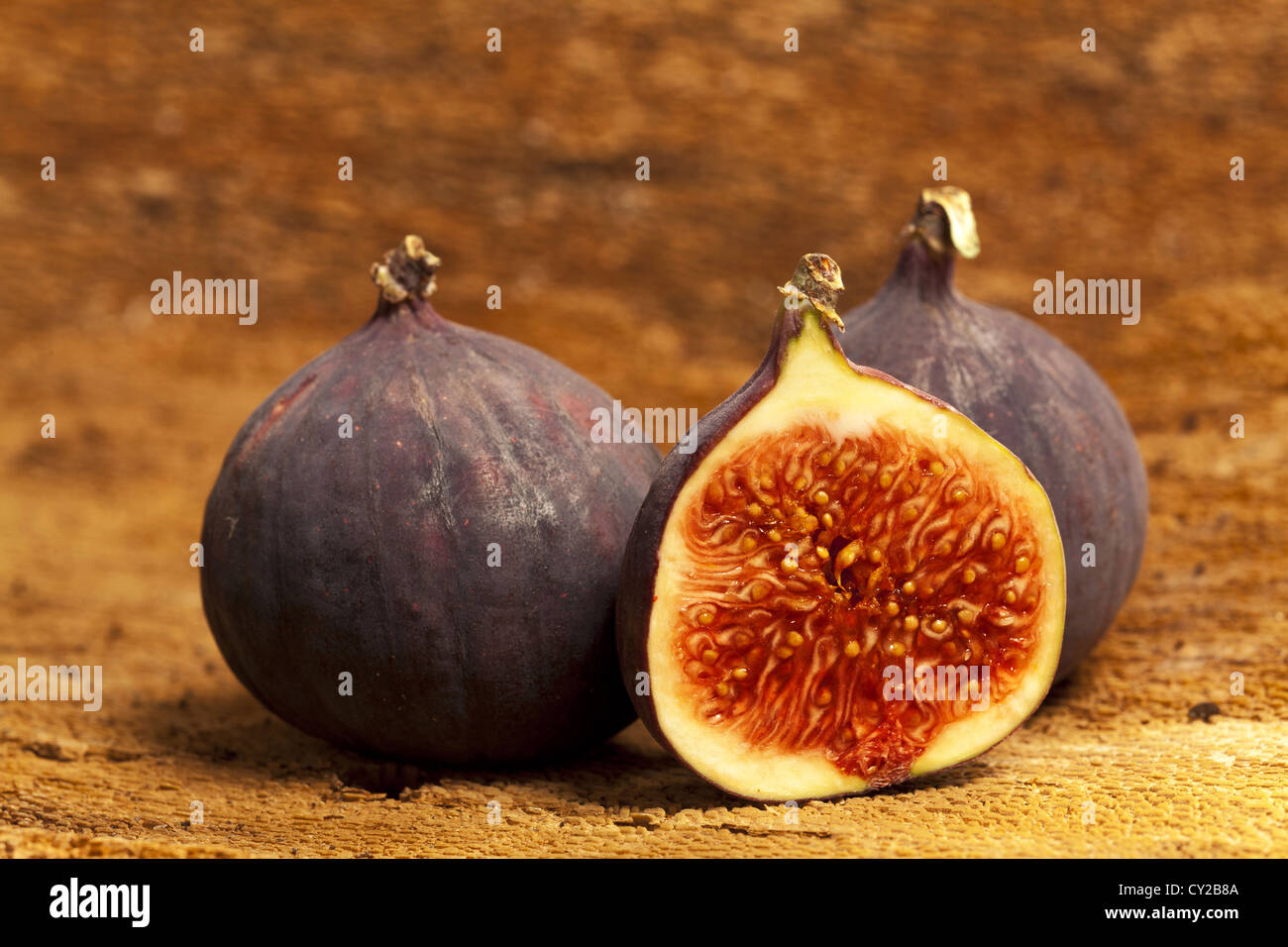 Two whole and a halved fig on old tree bark as background Stock Photo ...