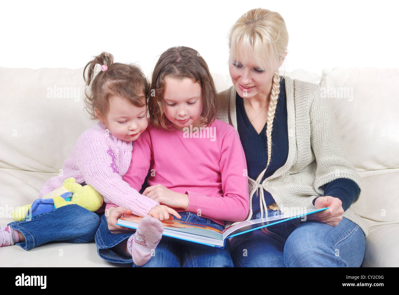 Mother and children sitting in living room reading book Stock Photo - Alamy