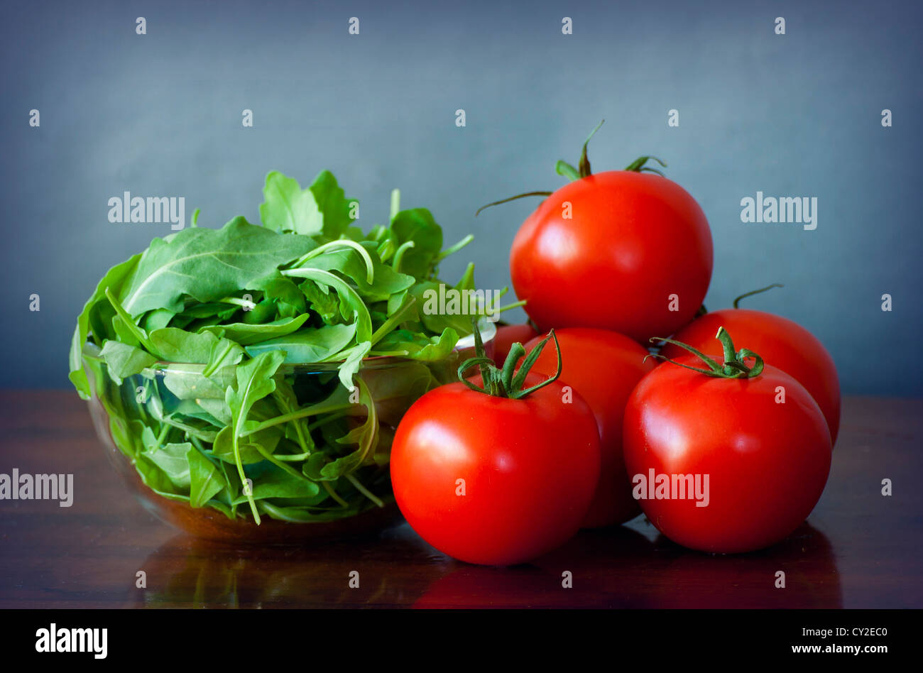 Fresh ingredients for salad, rucola and ripe red tomatoes on a wooden ...