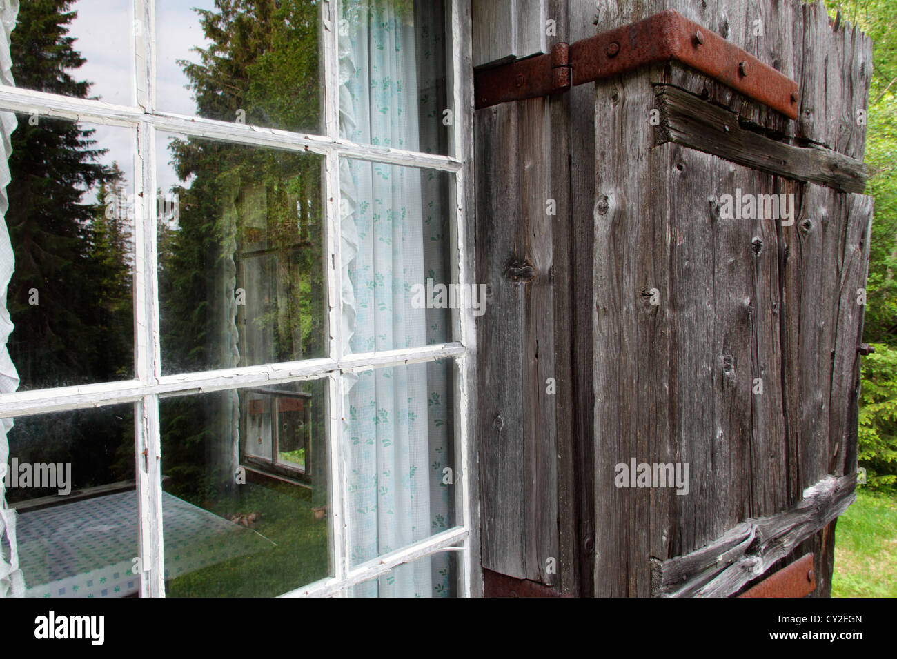 The forest is reflected in the window of a blockhouse. Thick shutters ...