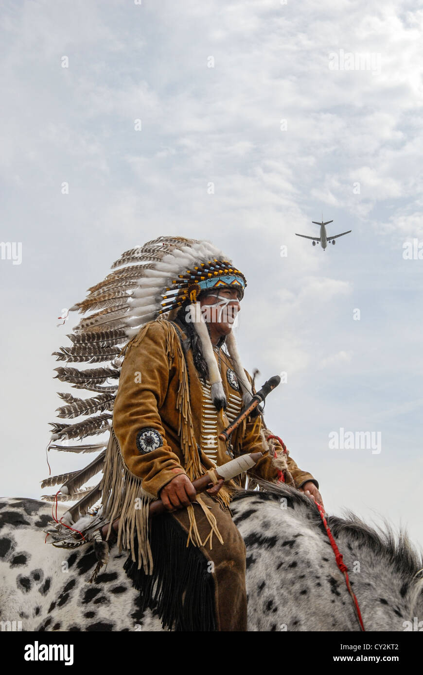 An airplane passes over a Native American in traditional dress Stock ...