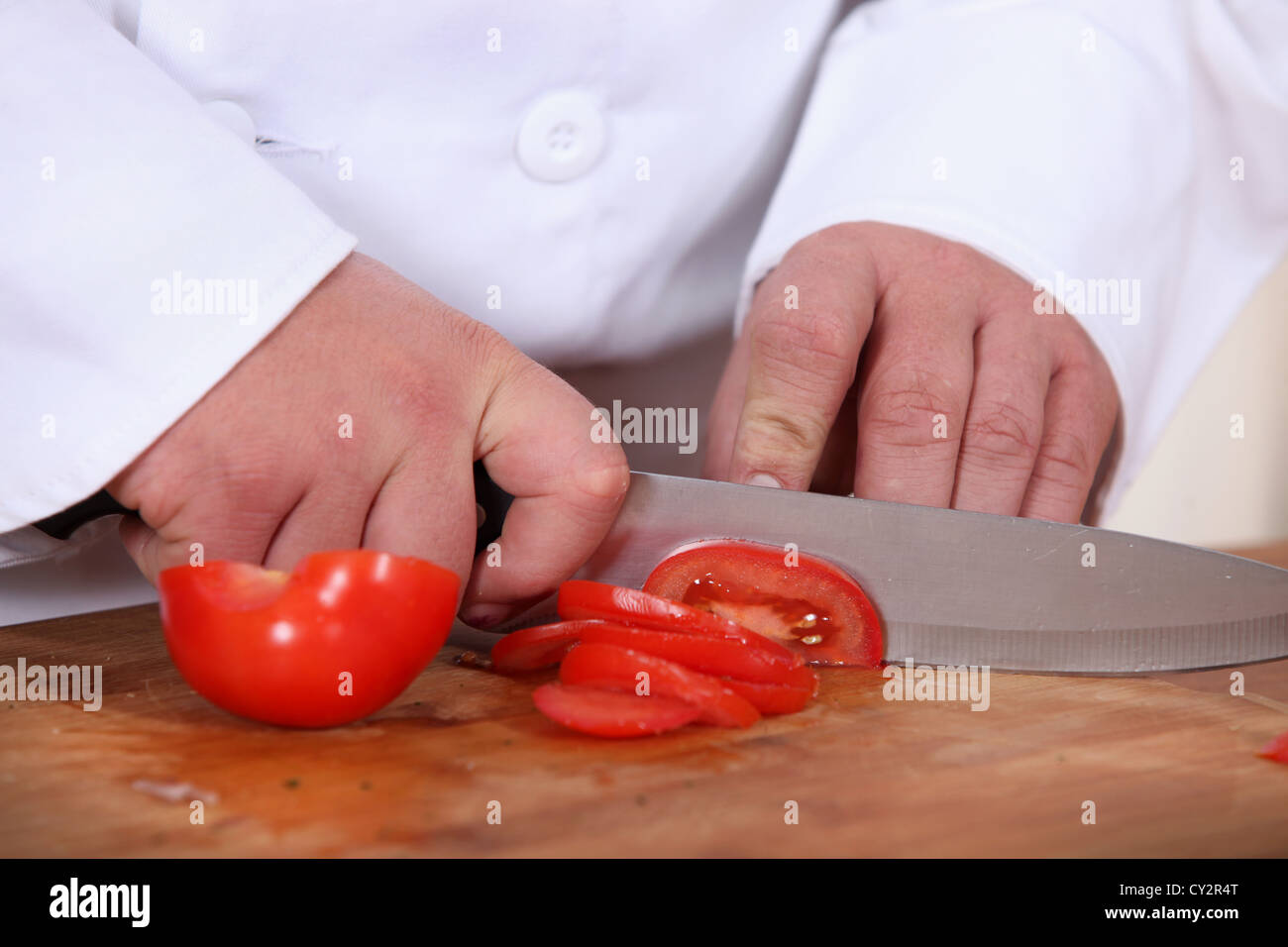 A cook slicing a tomato Stock Photo - Alamy