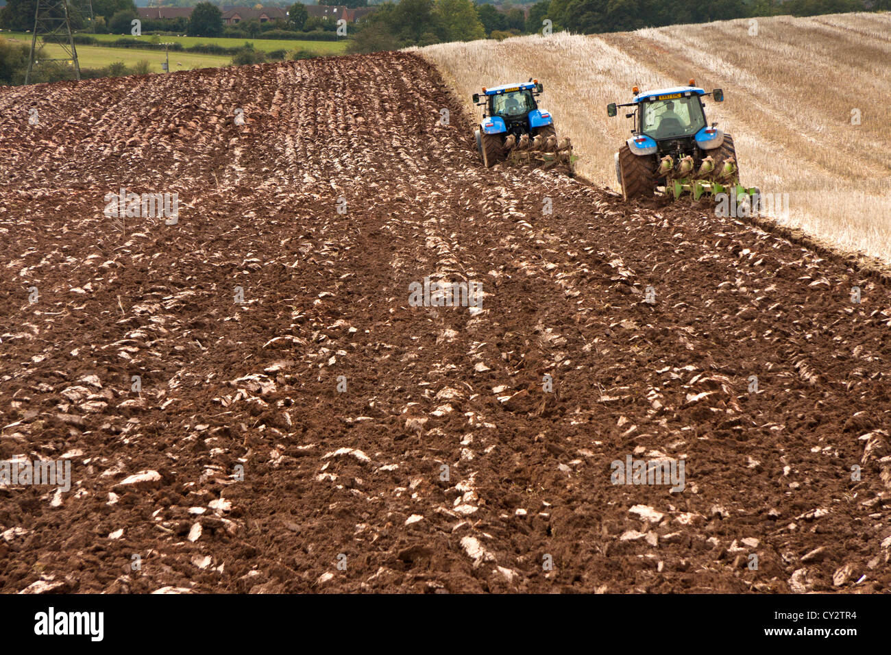 two tractors ploughing a field near Malvern hills Worcestershire ...