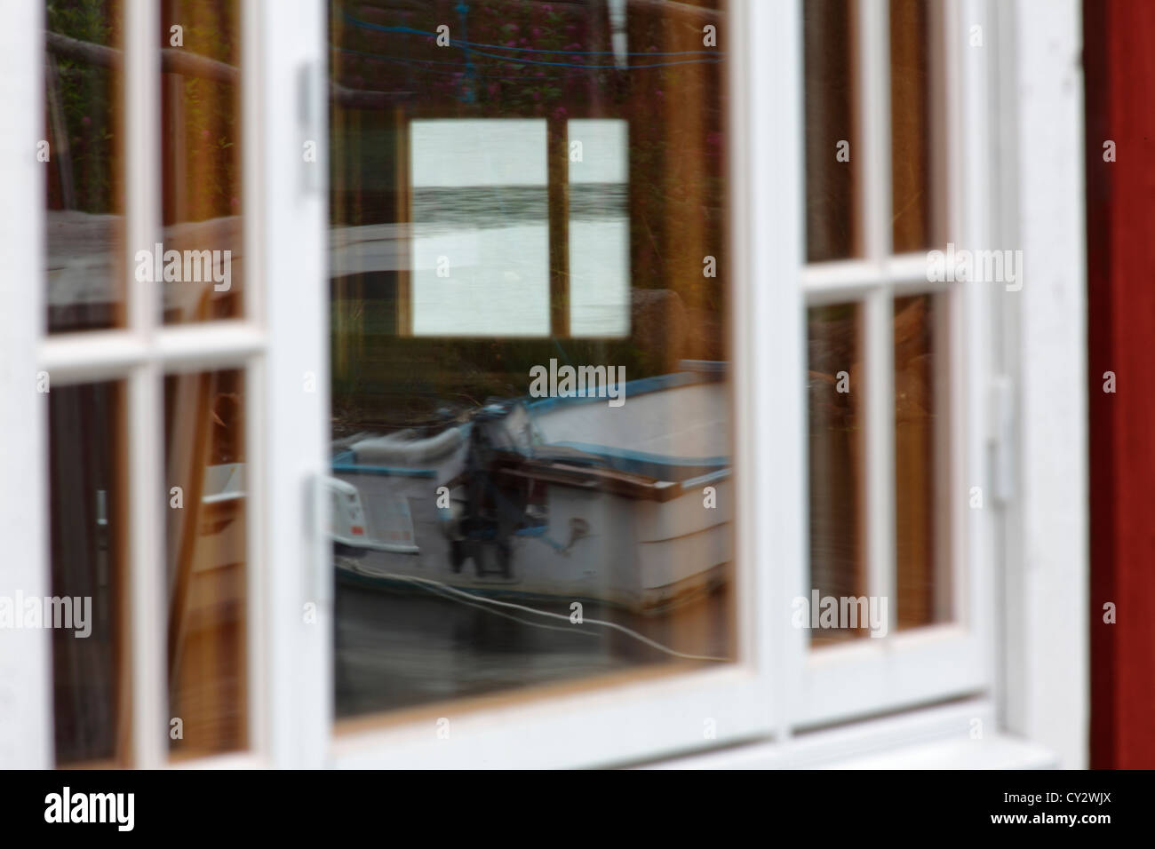 An open motorboat is reflected in the window of a boathouse Stock Photo ...