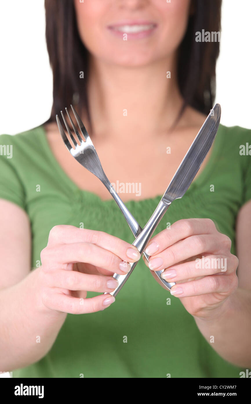 Woman holding up a knife and a fork Stock Photo - Alamy