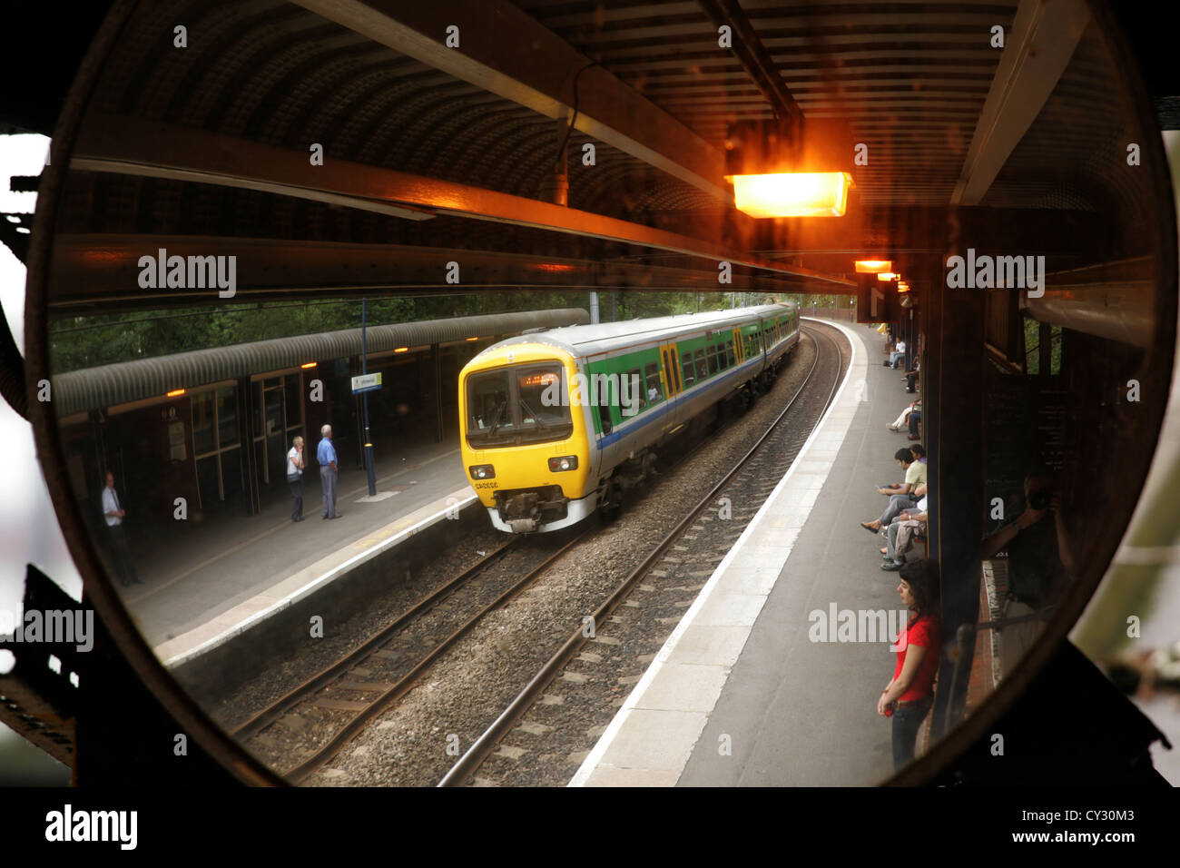 A cross city train is reflected in a mirror on the platform of ...