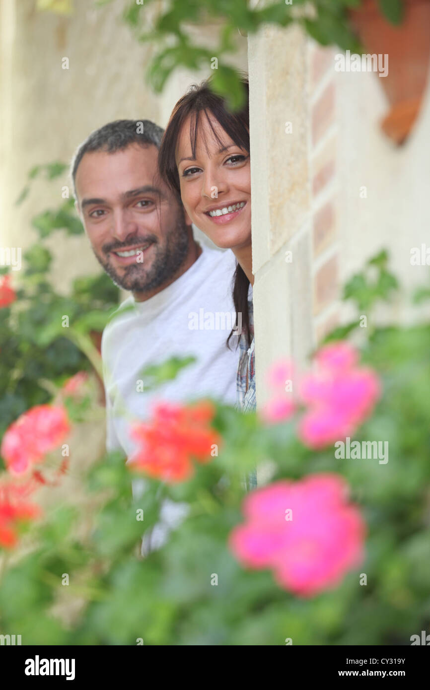 Couple hiding by a stone wall Stock Photo - Alamy