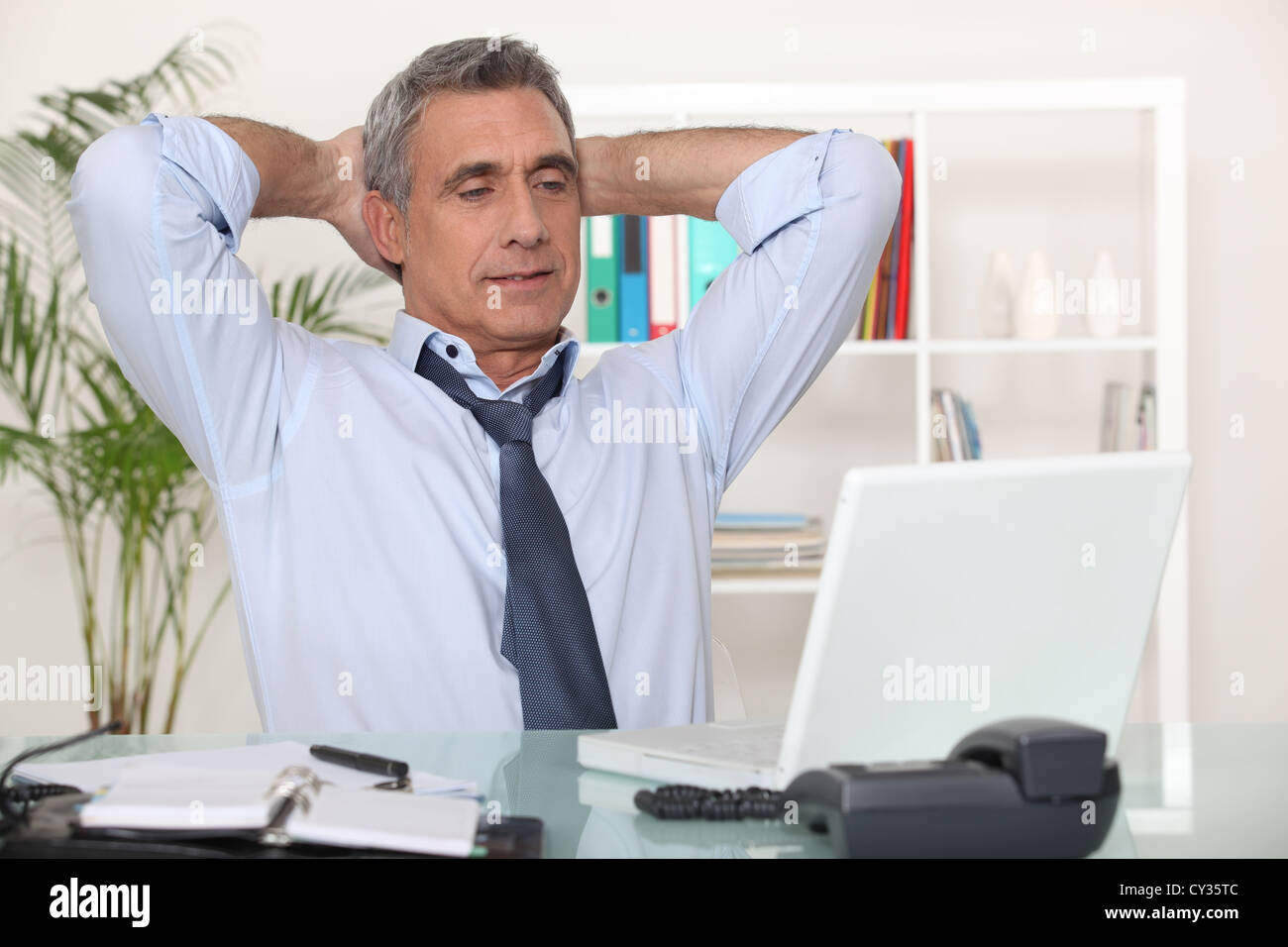 Businessman stretching at his desk Stock Photo - Alamy