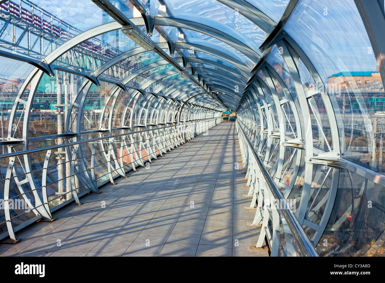 Steel and glass bridge for pedestrians crossing over the railway tracks ...