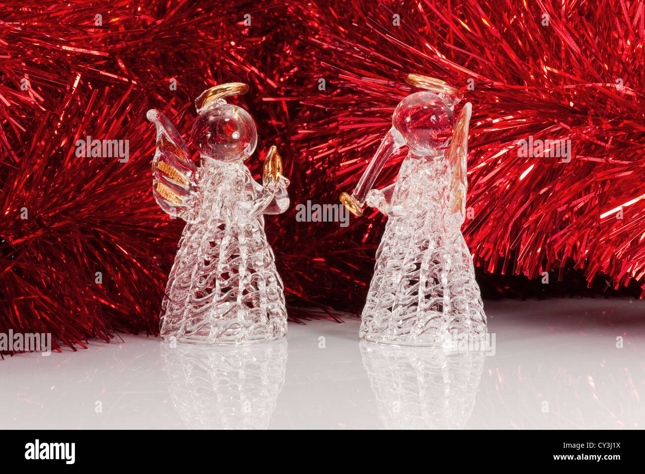 Two decorative glass angel and Christmas tree tinsel on white with ...