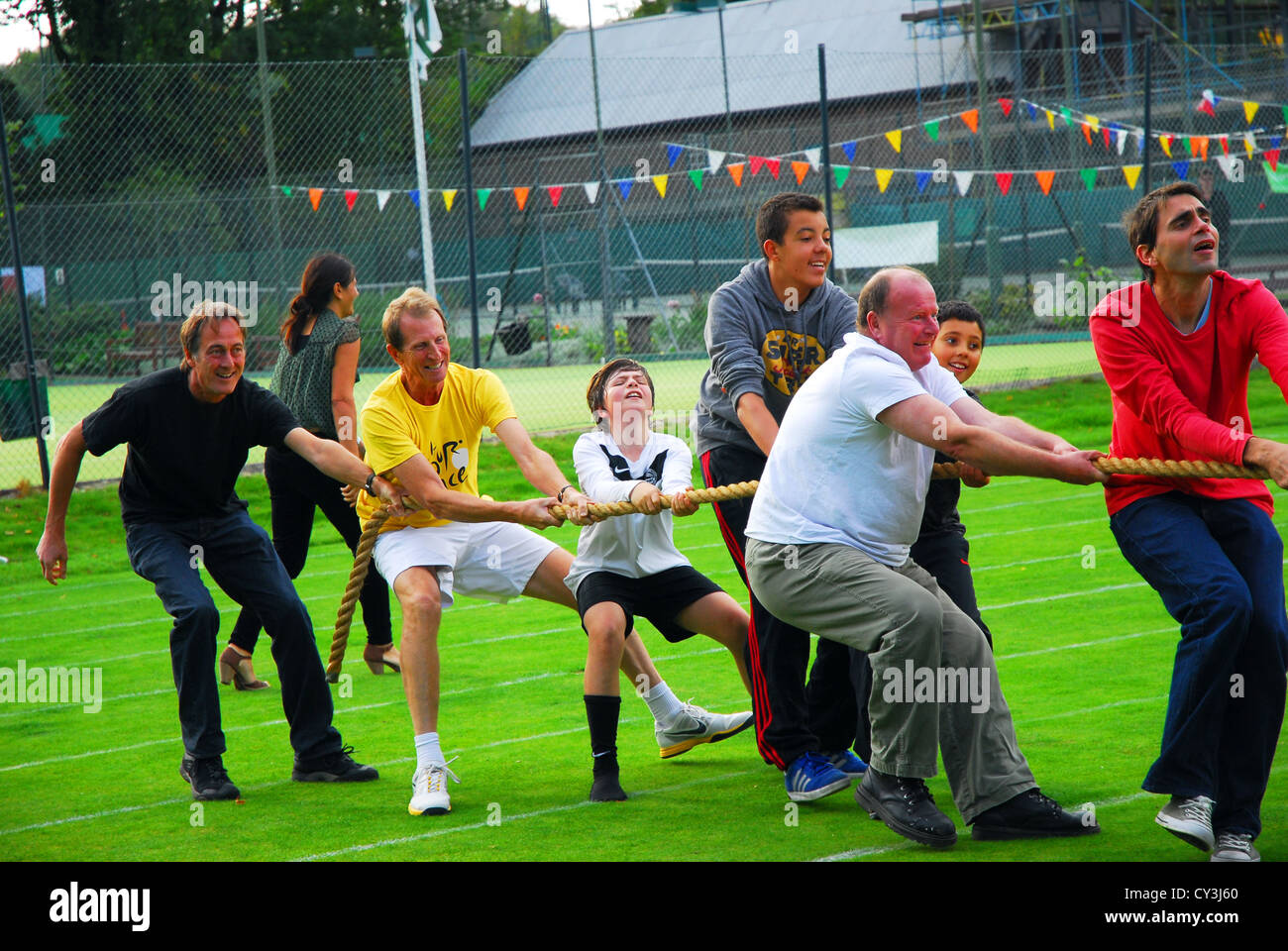 Members of a tennis club pull hard in a tug of war game on grass Stock ...