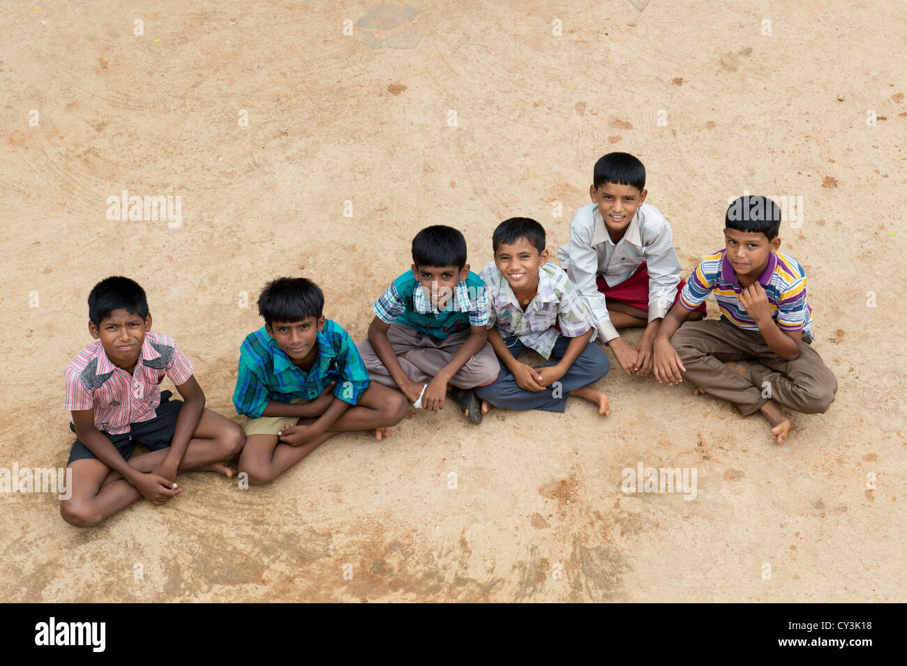 Young Indian village boys sitting cross legged on the ground in a rural ...