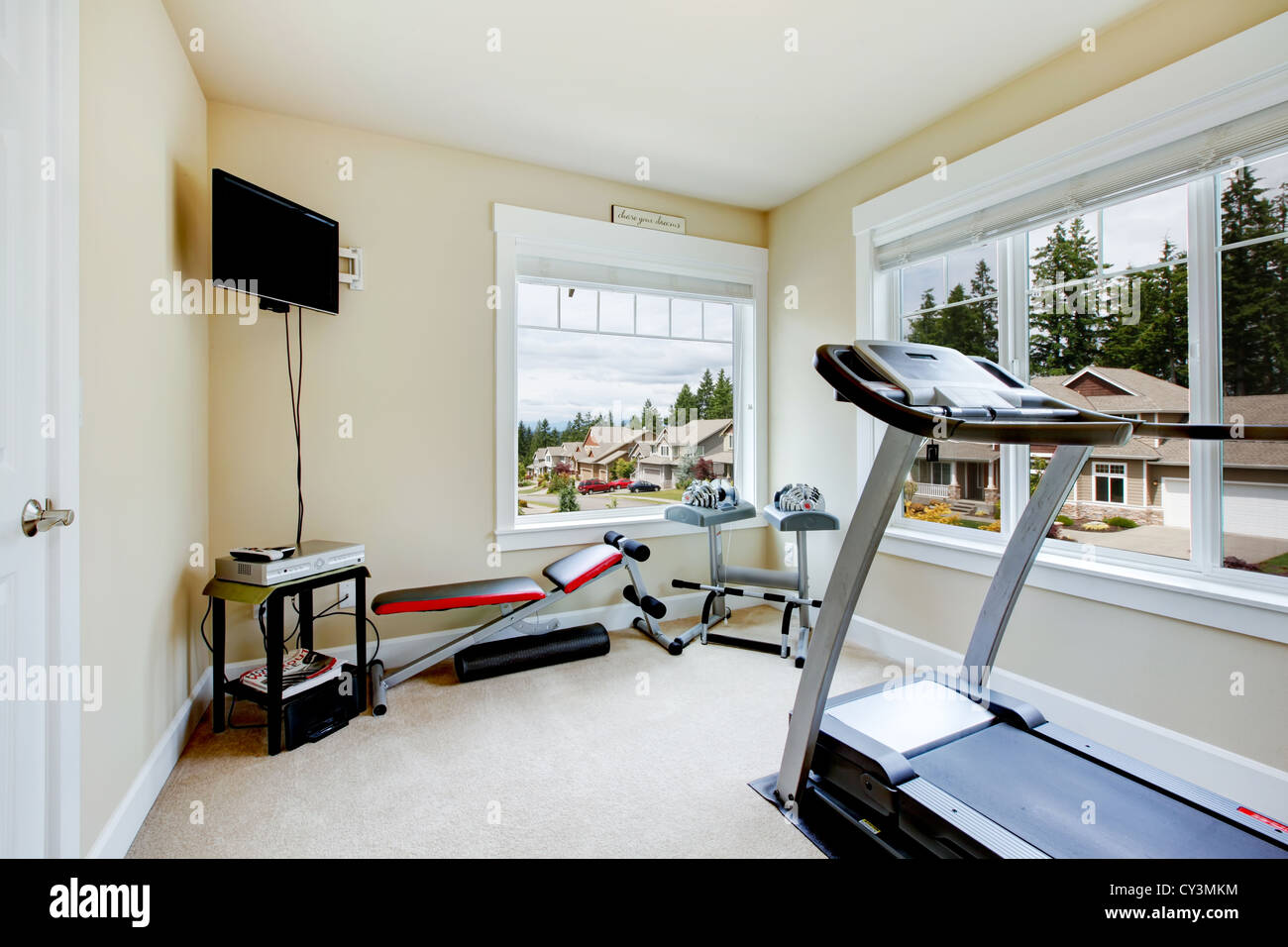 Home gym with equipment, weights and TV with two large windows Stock ...