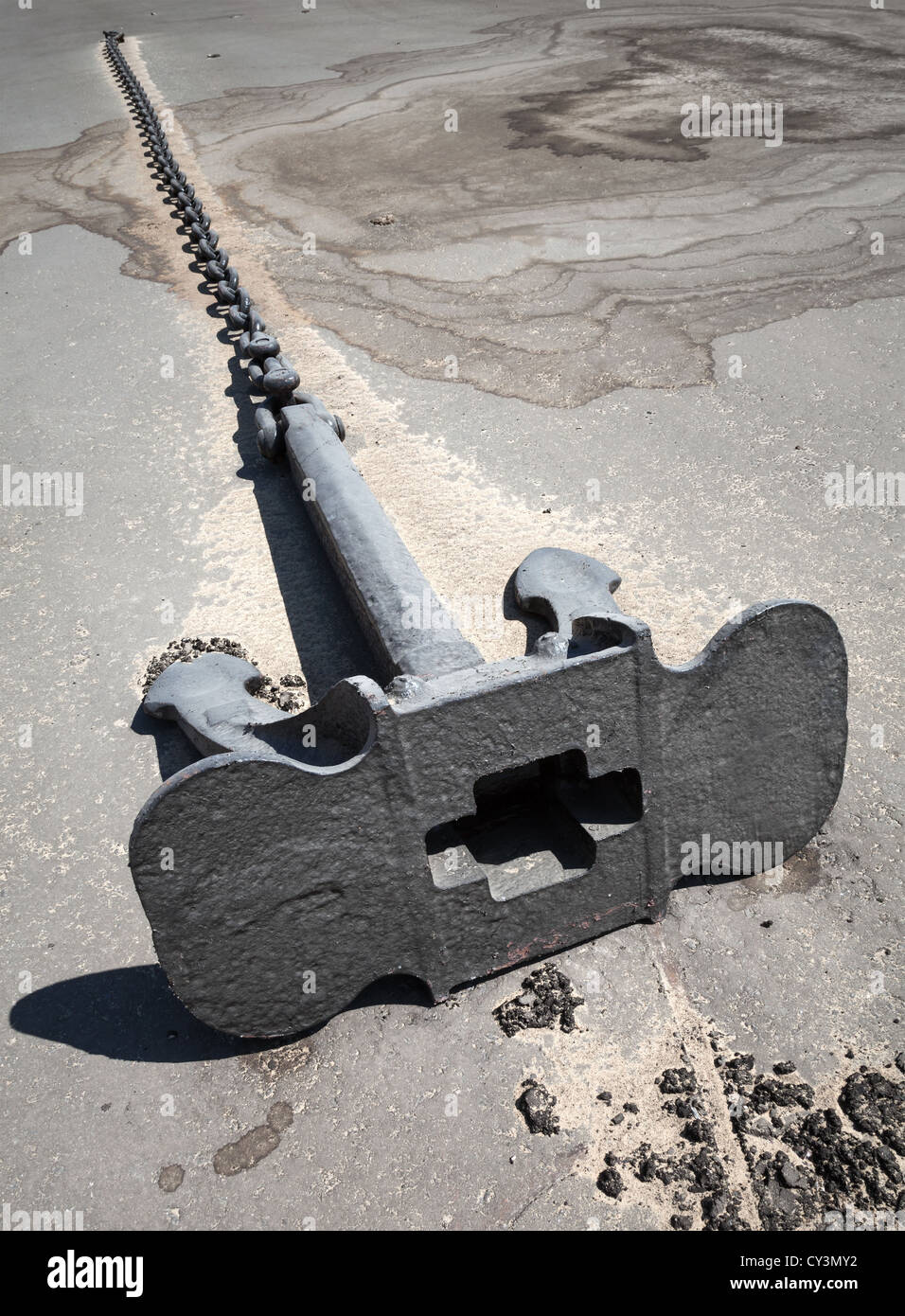Large old ship's mooring anchor with chain on dry ground in the port ...