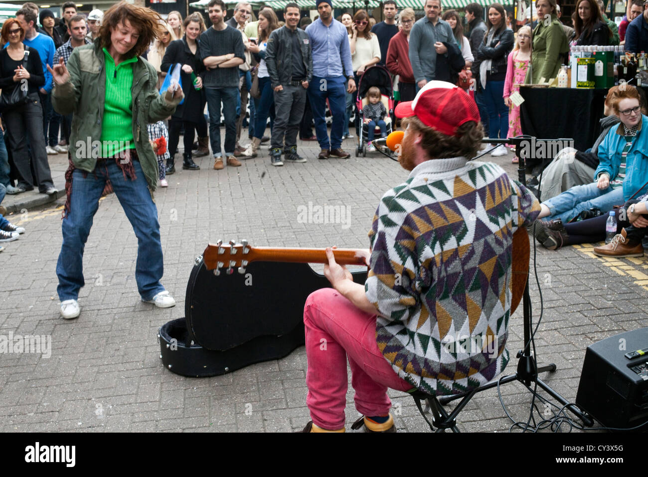 A street performer plays guitar to an audience in Broadway Market ...