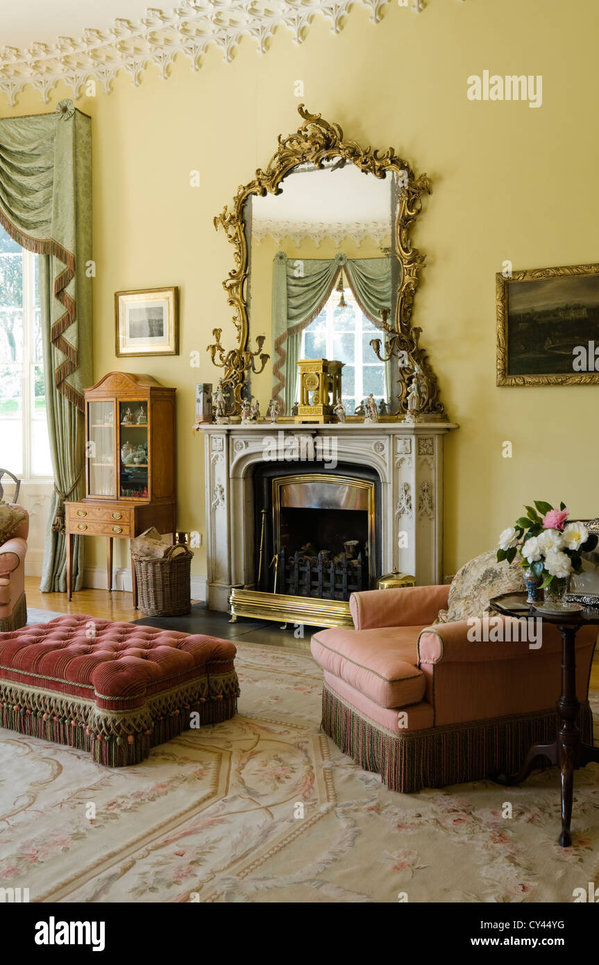 Yellow drawing-room with gilt framed mirror, mantelpiece and red tufted ...