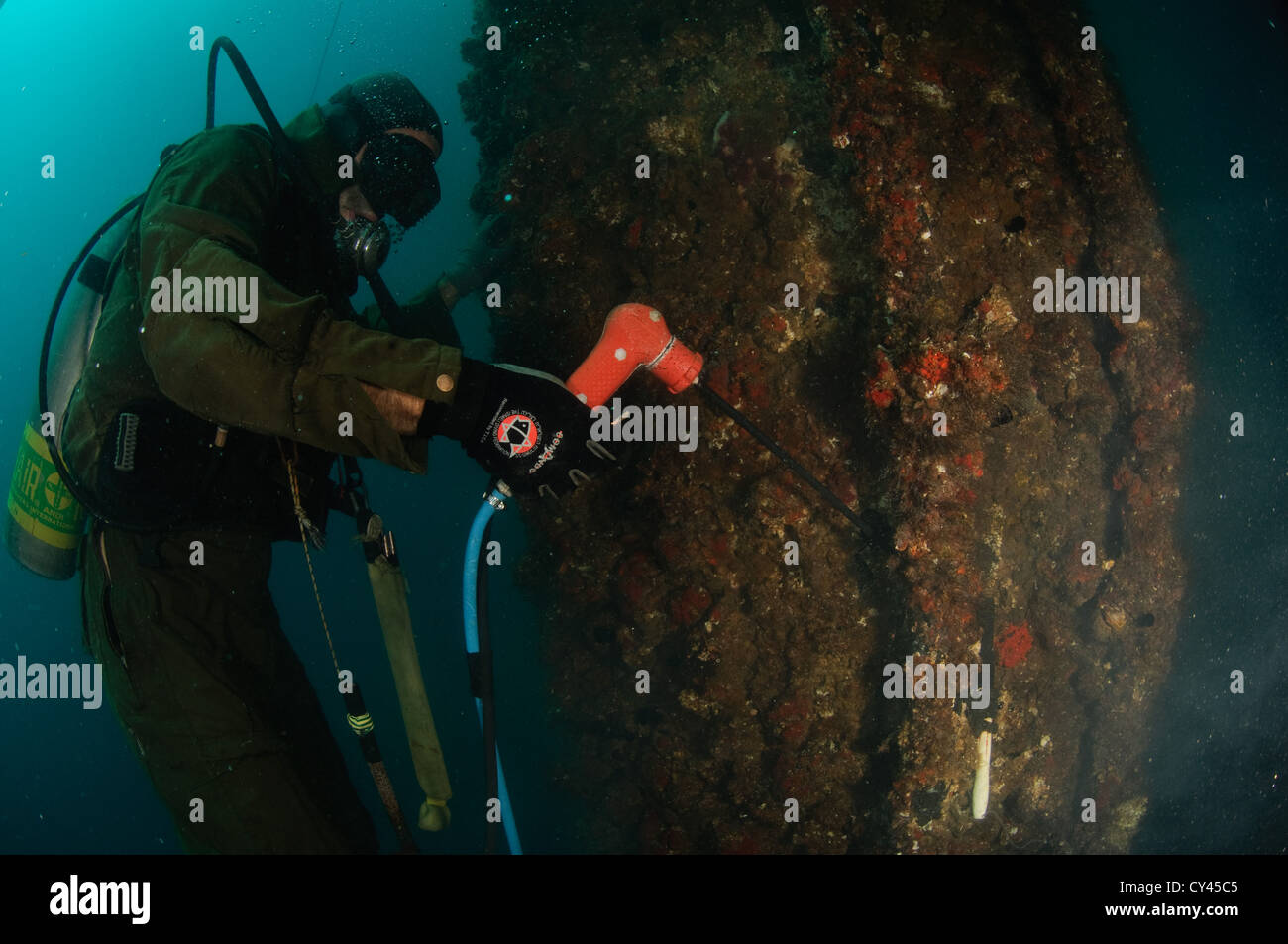 Commercial diver welding pipes underwater. Cables from the surface are ...