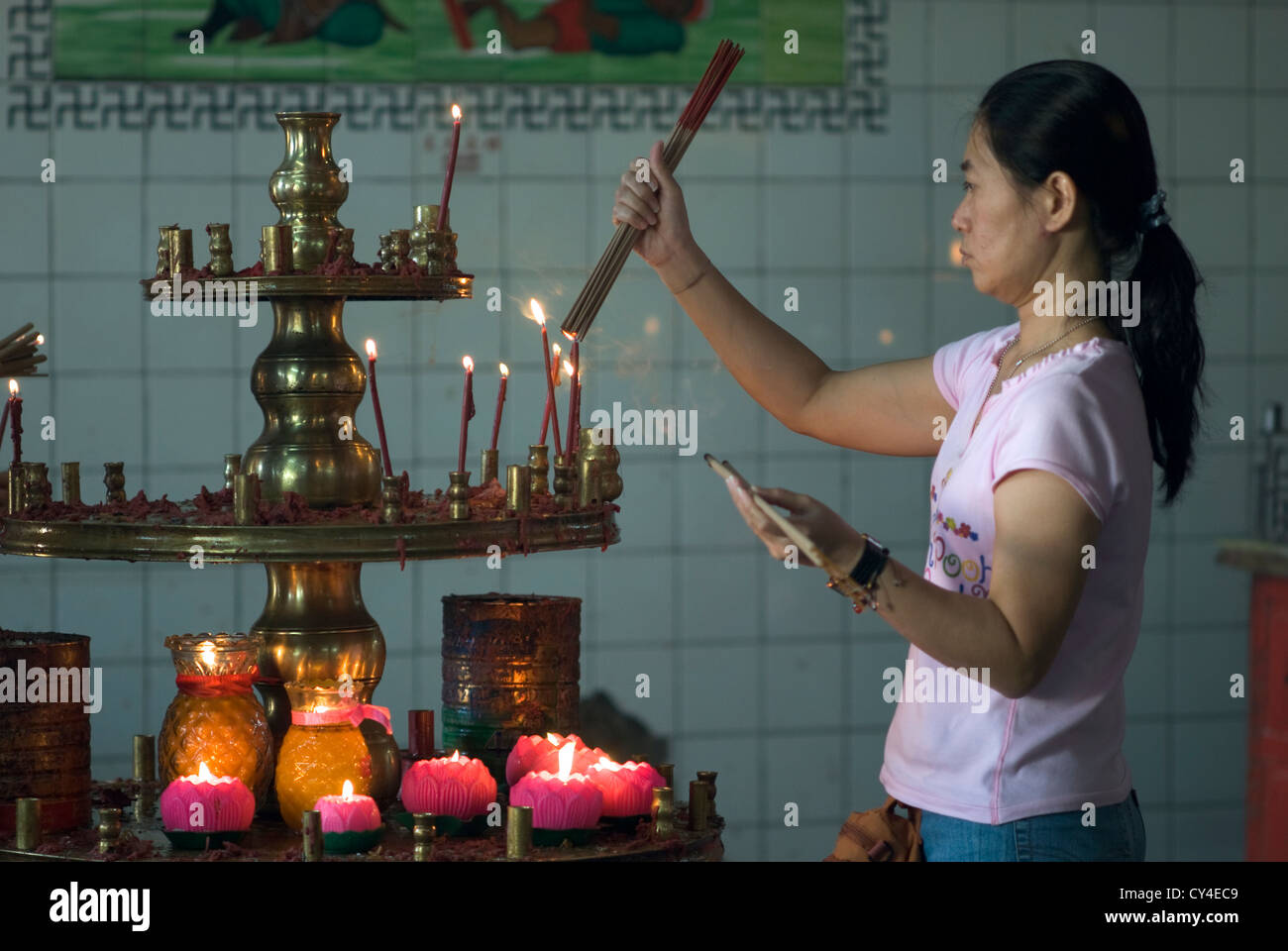 A woman lights incense as offerings at the Goddess of Mercy temple in ...