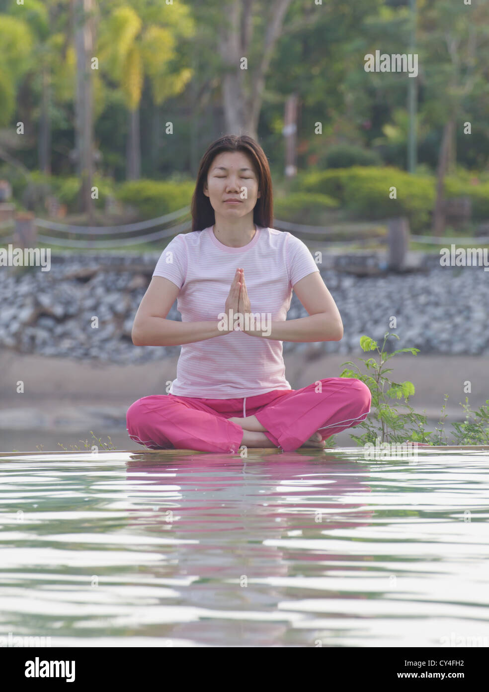 Asian lady is doing meditation near pond Stock Photo - Alamy