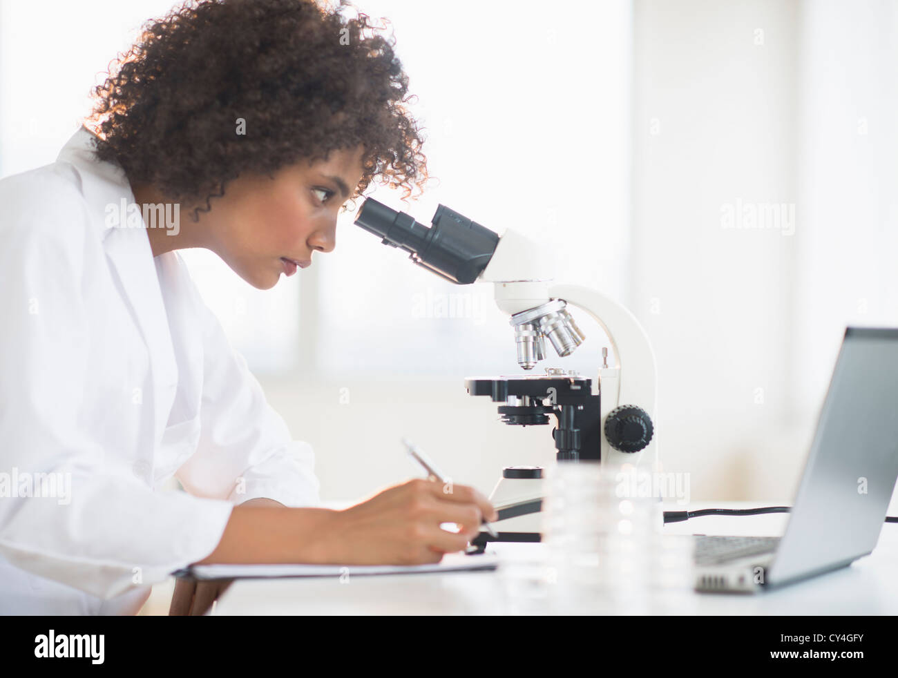 USA, New Jersey, Jersey City, Woman using microscope in laboratory ...