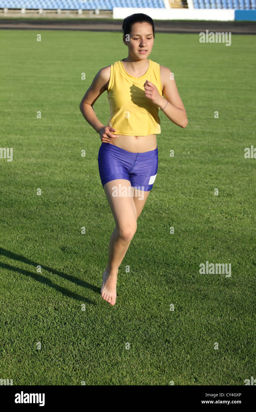 Beautiful teenage sport girl running on the grass Stock Photo - Alamy