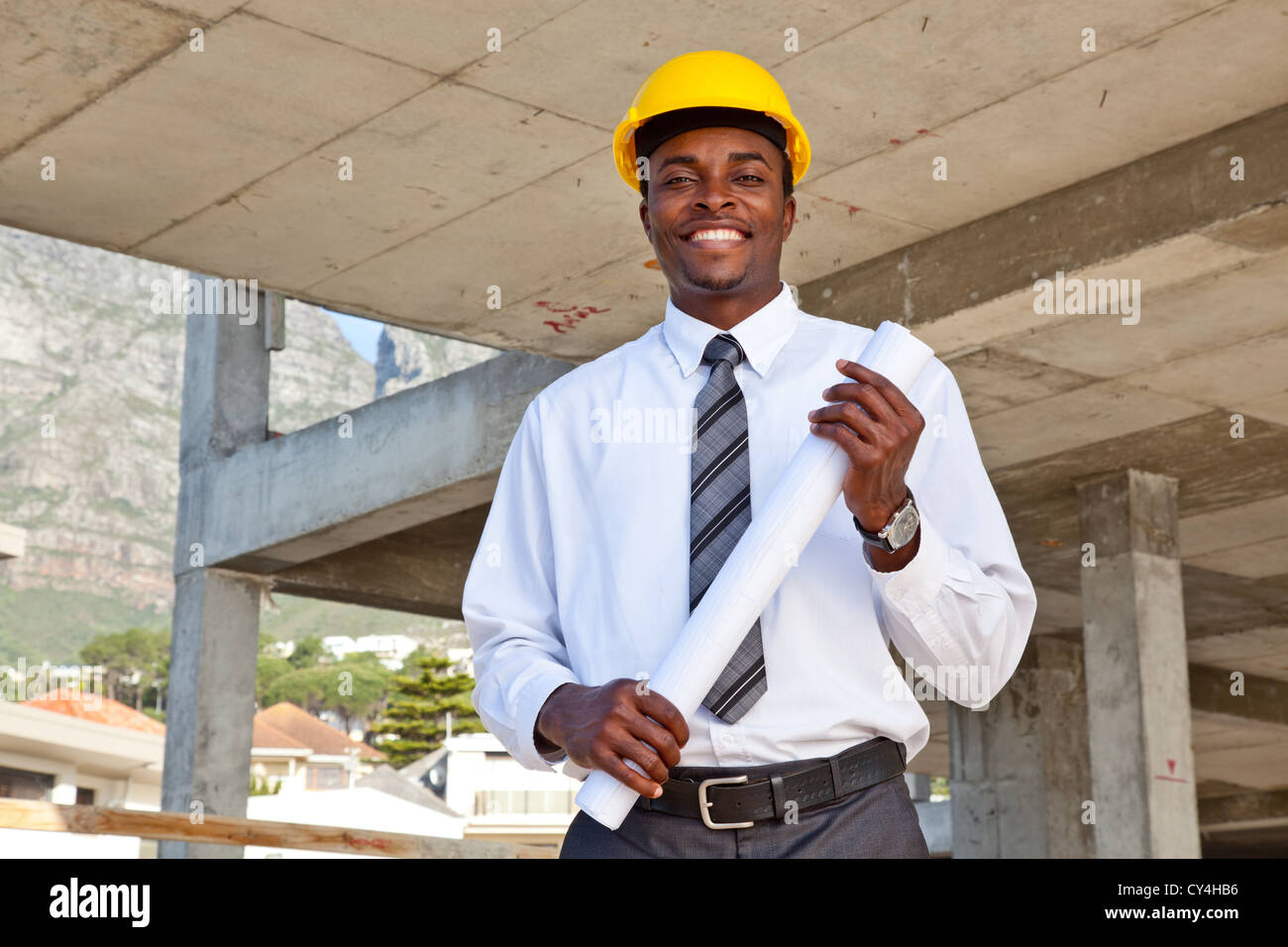 African man in a construction site wearing a hard hat and holding ...