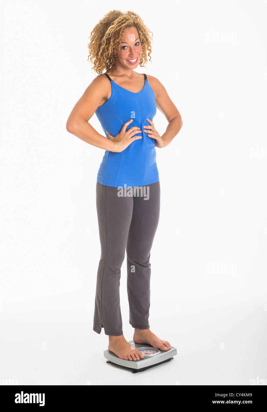 Portrait of young woman standing on weight scale, studio shot Stock ...