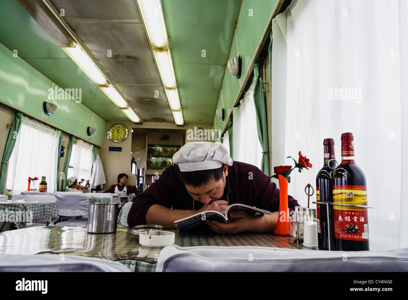 Chinese cook on a train dining car reading a magazine during a break ...