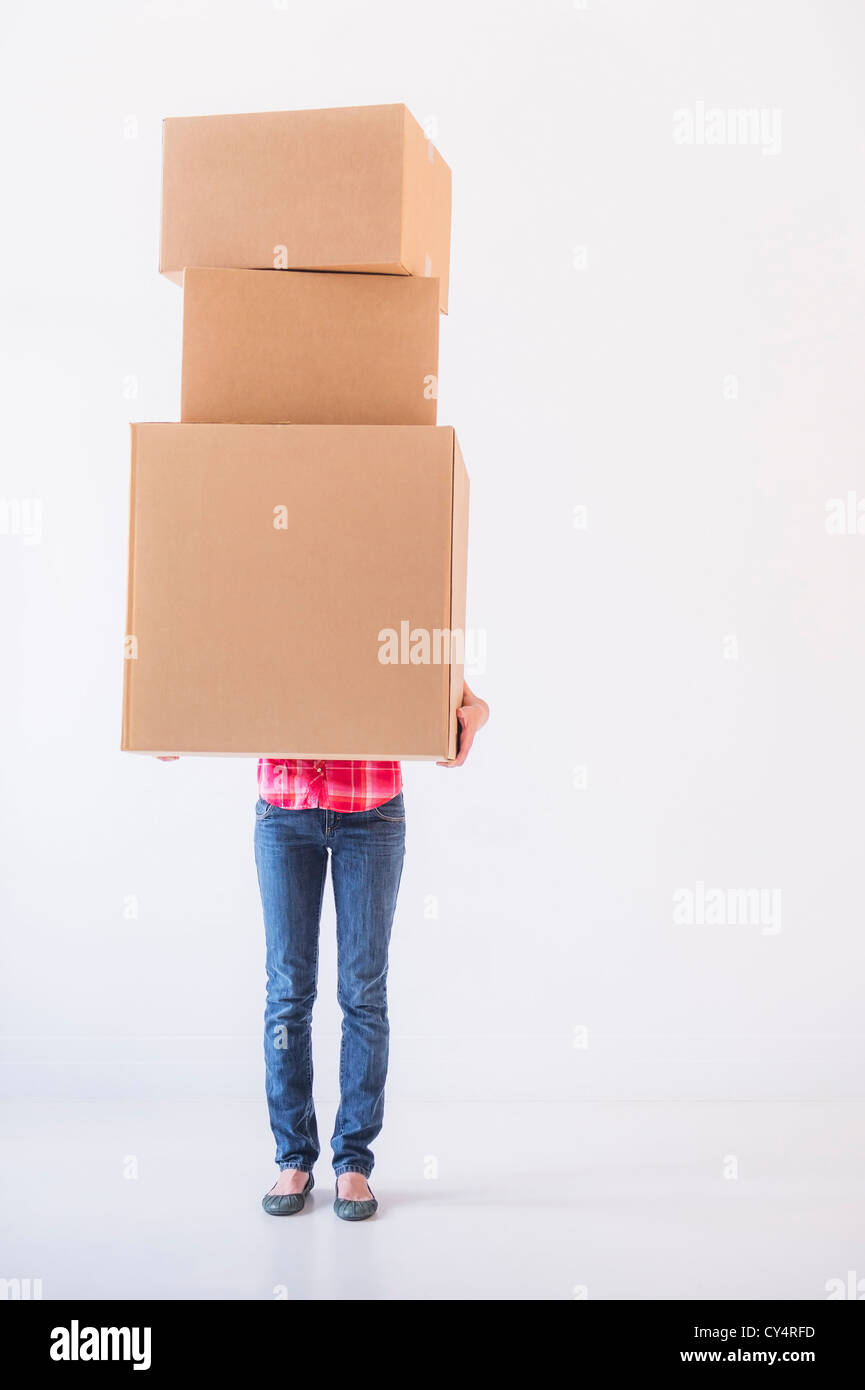 Studio shot of young woman carrying stack of boxes Stock Photo - Alamy