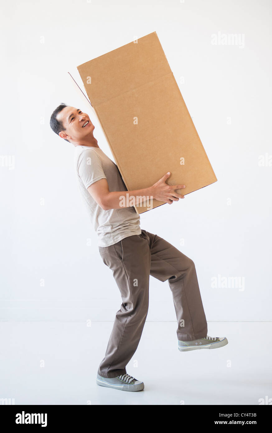 Mid adult moving cardboard heavy box Stock Photo - Alamy