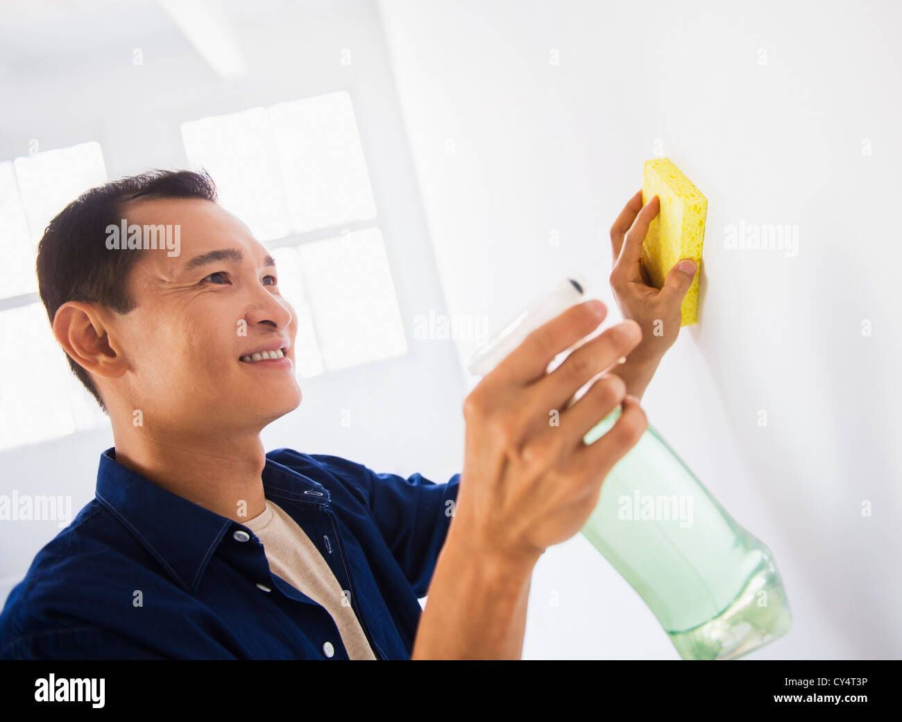 Man washing white walls with spray and yellow sponge Stock Photo - Alamy