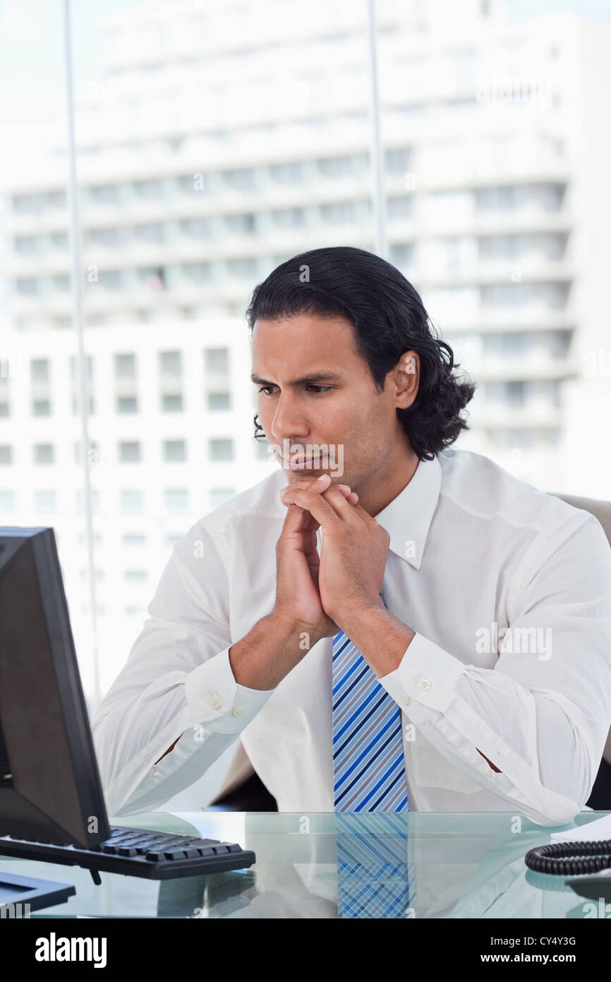 Portrait of a businessman thinking while using a computer Stock Photo ...