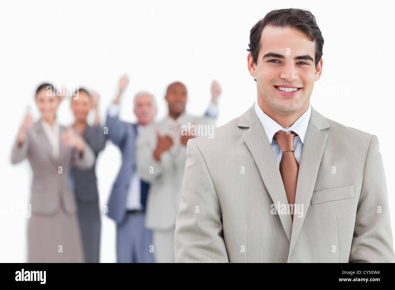 Smiling salesman with cheering team behind him Stock Photo - Alamy
