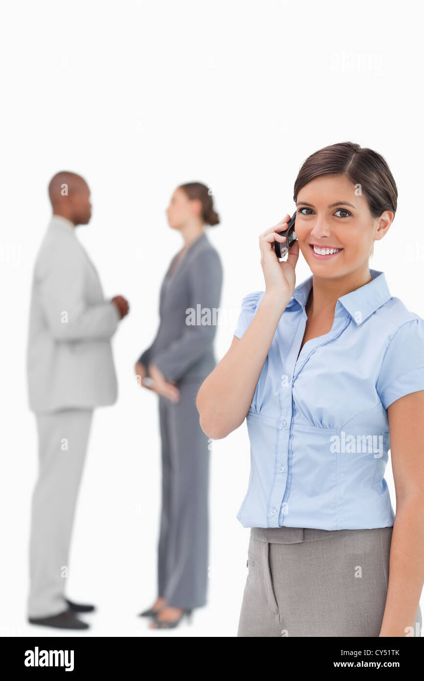 Smiling saleswoman on the phone with associates behind her Stock Photo ...