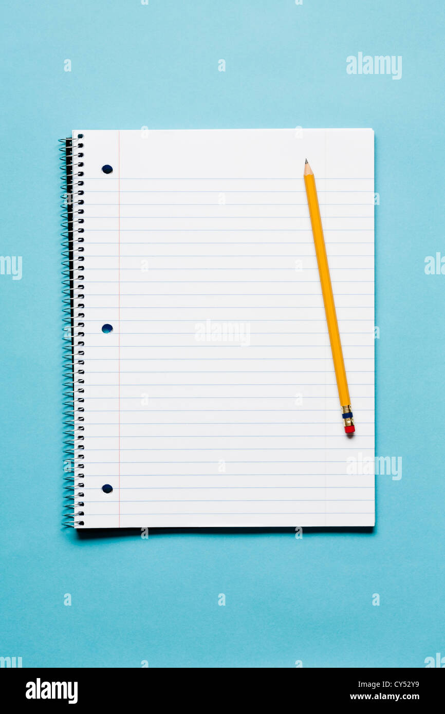Single yellow sharpened pencil with blank spiral notebook on blue ...