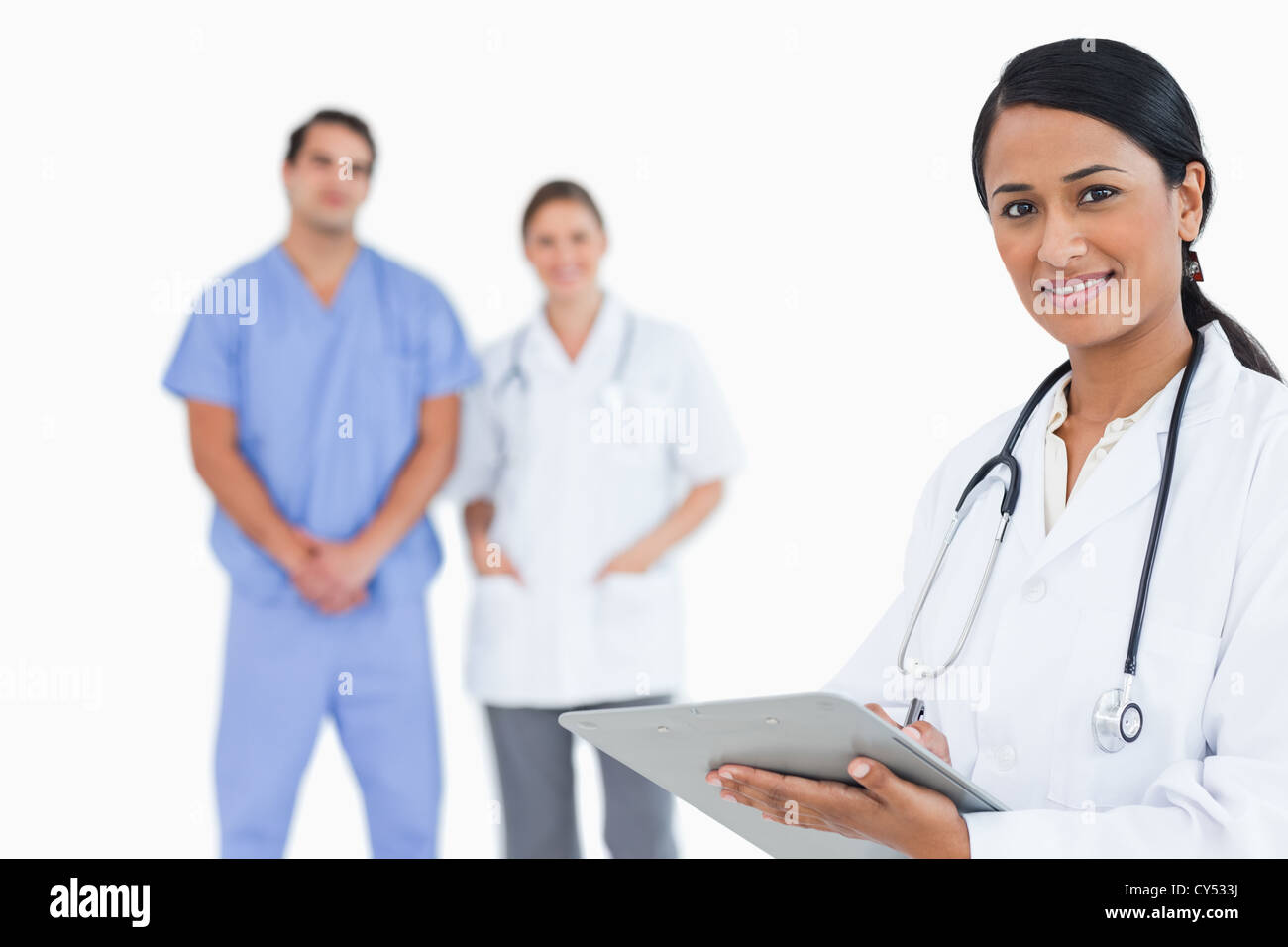 Doctor with notepad and colleagues behind her Stock Photo - Alamy