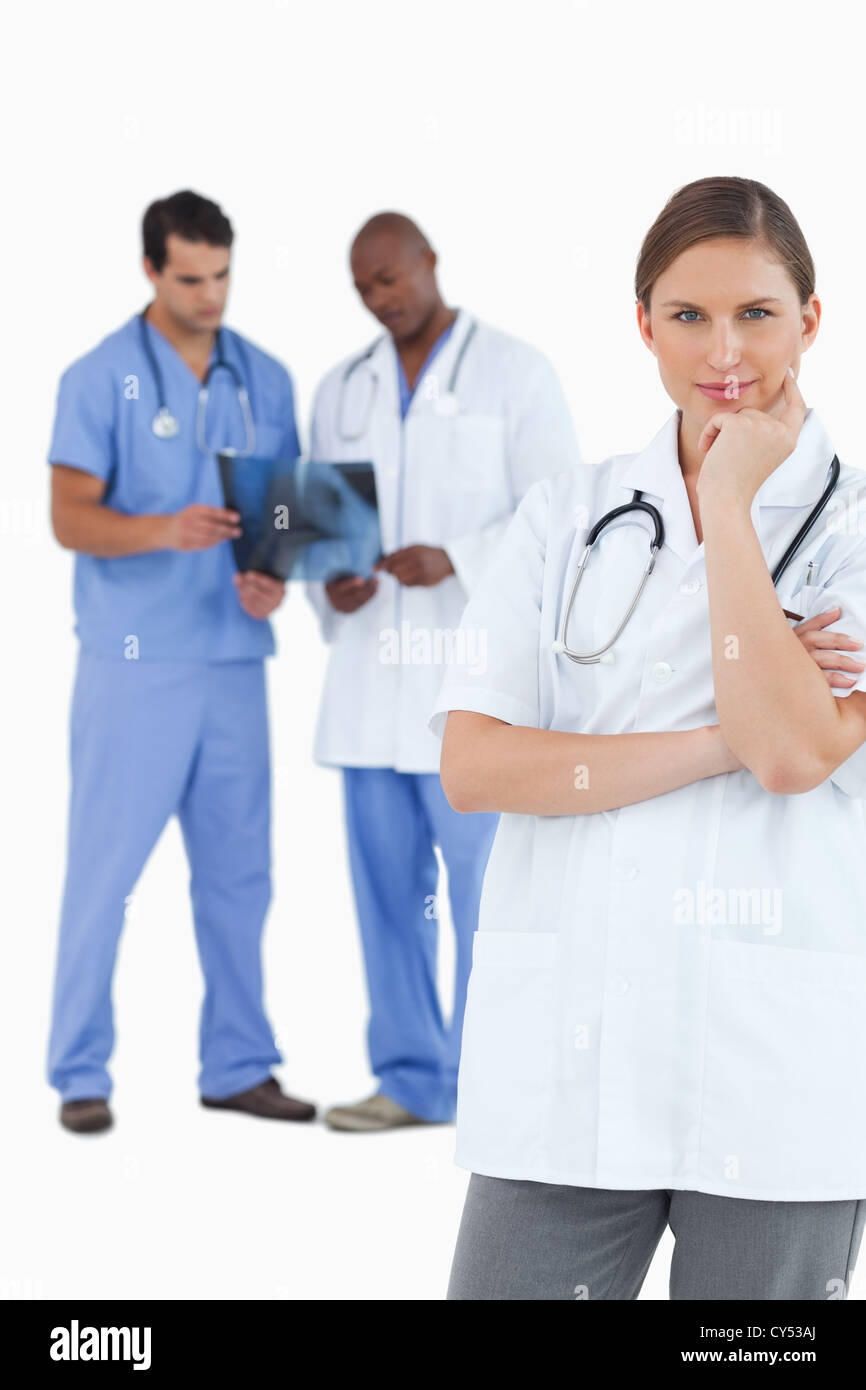 Thinking doctor with colleagues behind her Stock Photo - Alamy