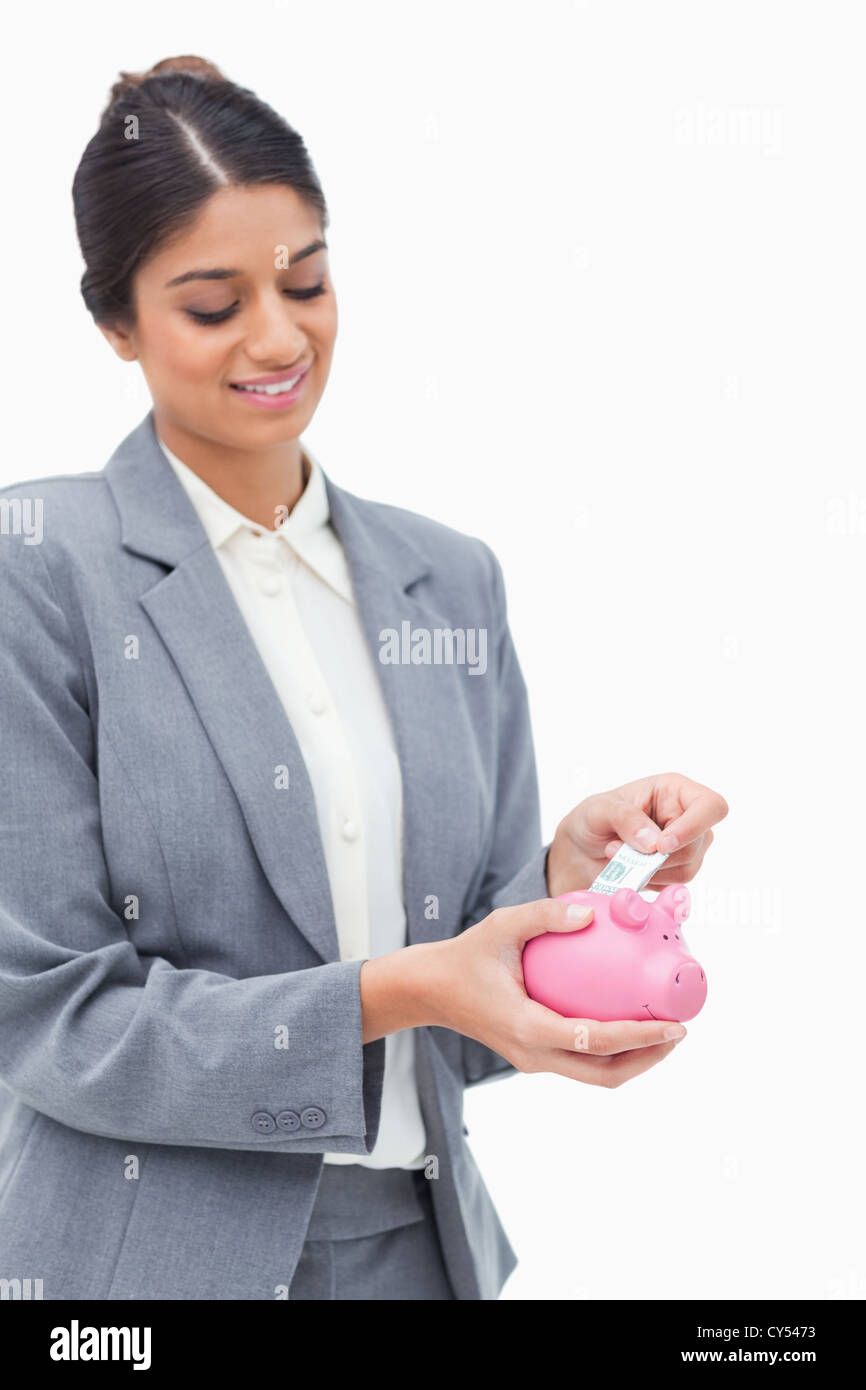 Smiling bank assistant putting bank note into piggy bank Stock Photo ...
